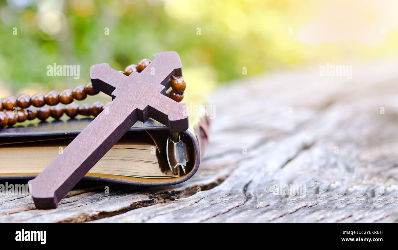 Dark red wooden cross leaning against an old open book symbolizing the ...