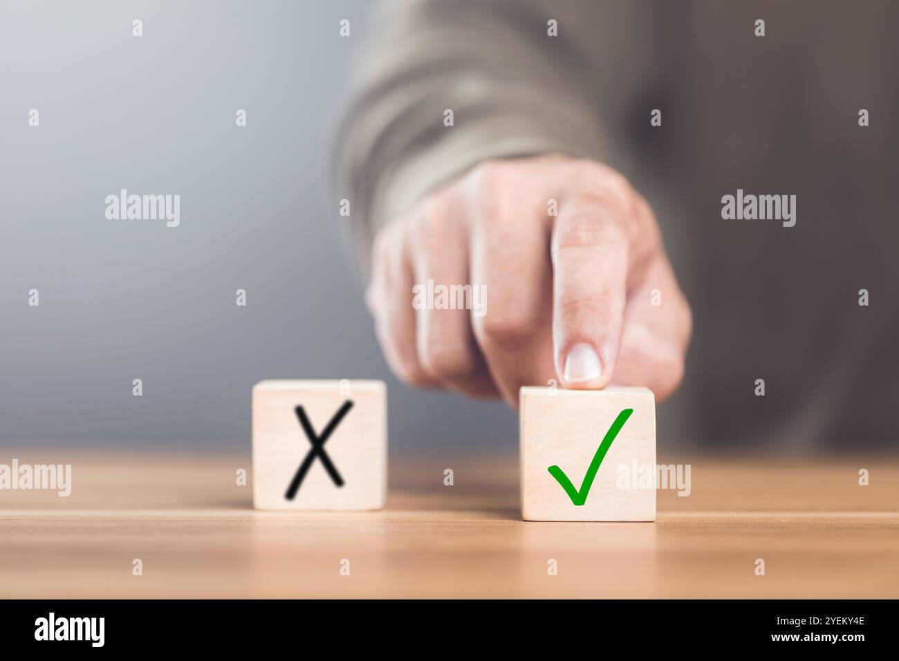 Man choosing between a checkmark and an 'X' symbol on wooden blocks ...