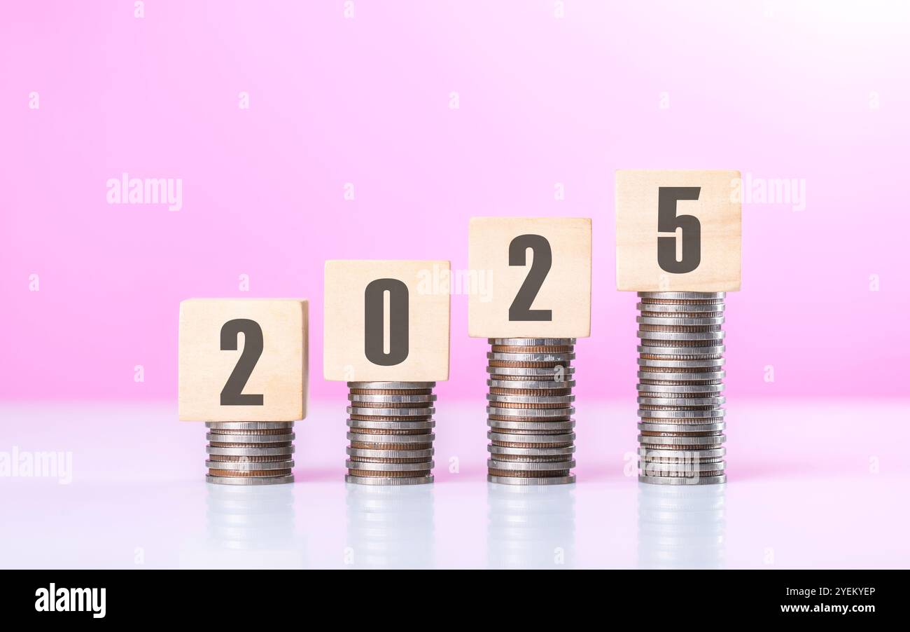 Stack of coins placed on top of a wooden block labeled '2025.' The ...