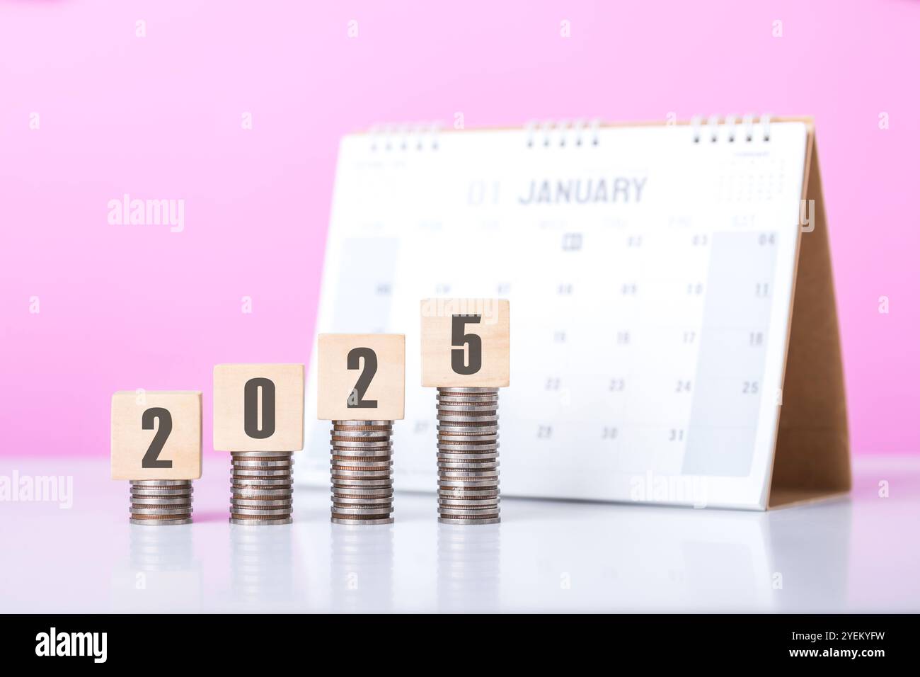 Stack of coins beside a wooden block labeled '2025' and a calendar ...