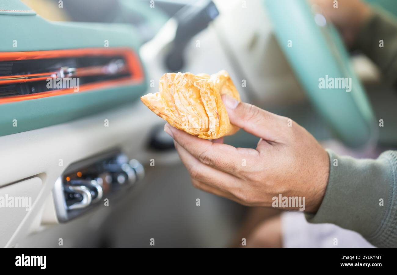 A car owner enjoys a pie while seated inside. Highlighting the impact ...
