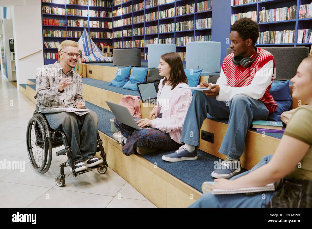Group of students interacting in library, discussing ideas while using ...