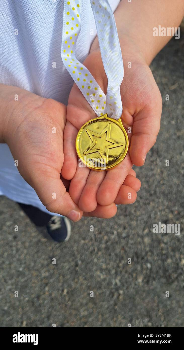 Child proudly holding a first place gold medal with a star on it Stock ...
