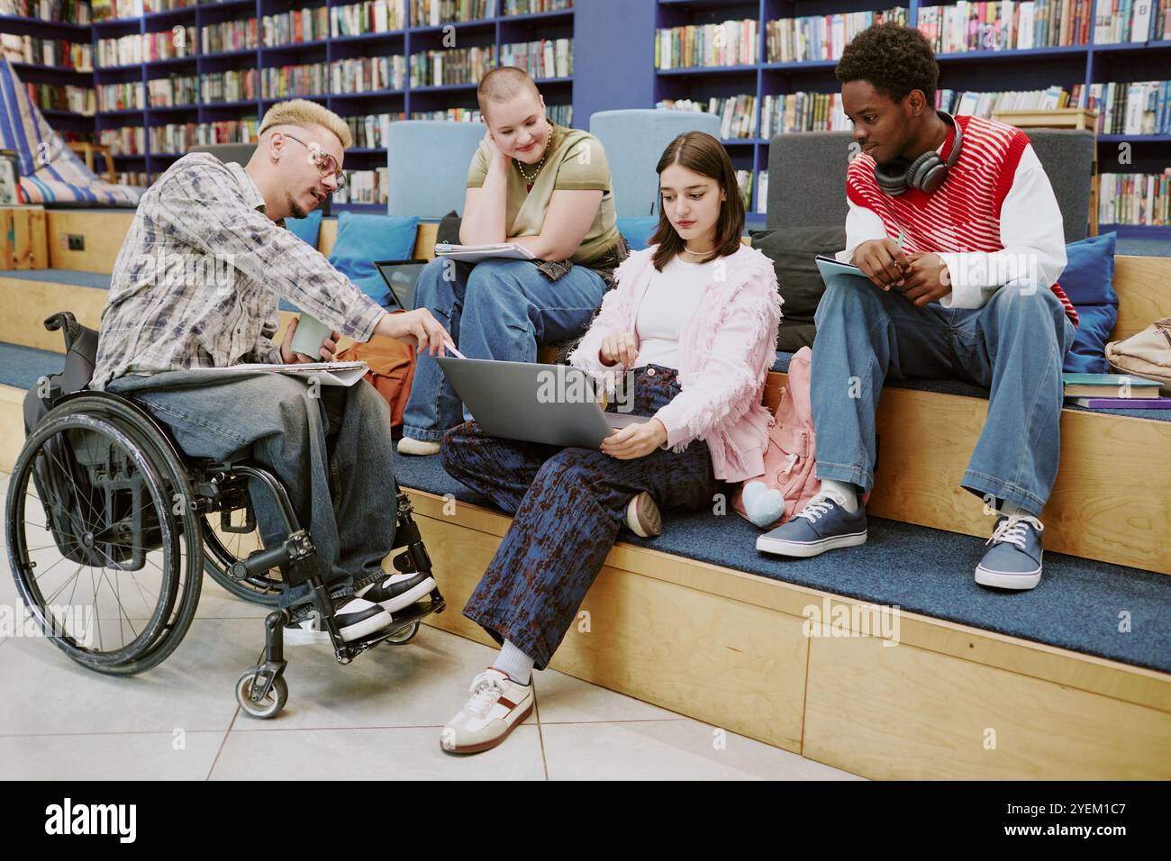 Group of diverse students studying in modern library, using laptop and ...