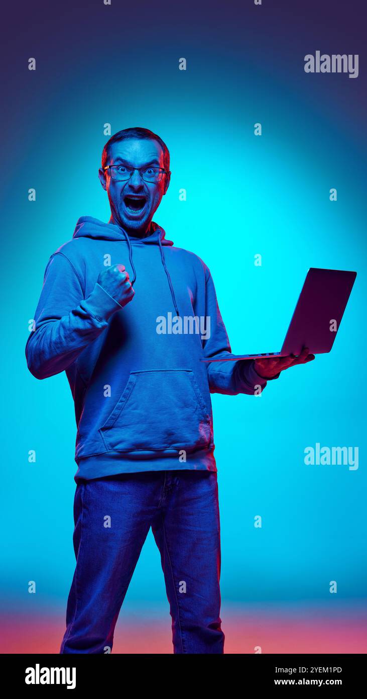 Football fan, young man dressed casually, holding laptop and clenching ...