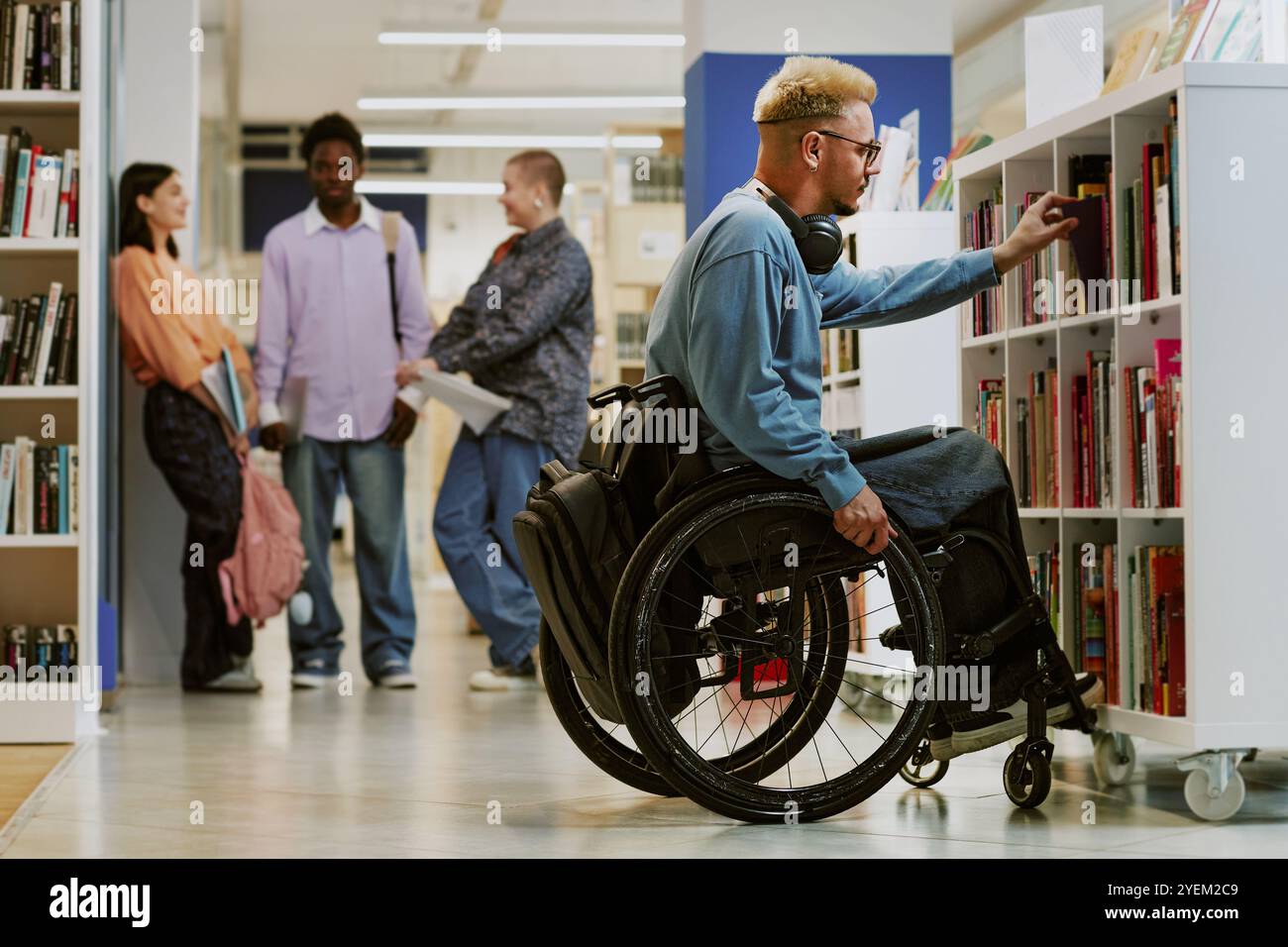 Person in a wheelchair browsing books at a modern library, with diverse ...