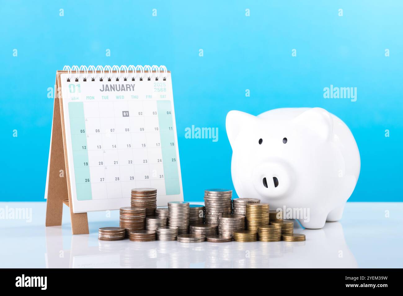Stack of coins, a piggy bank, and a 2025 desk calendar placed together ...