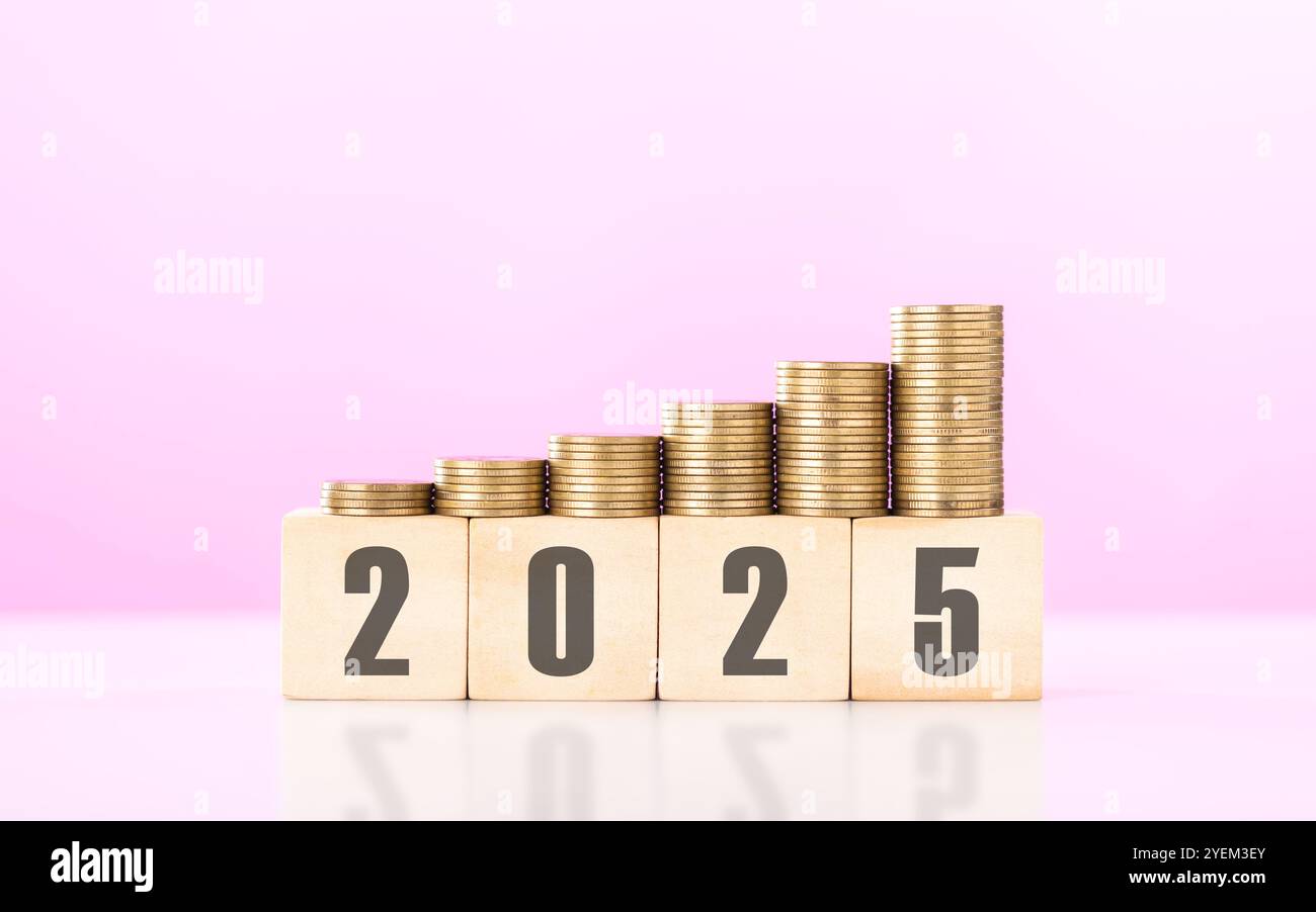 Stack of coins placed on top of a wooden block labeled '2025.' The ...