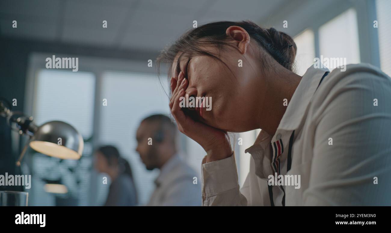 Call center office: Close up of tired Asian woman holding head, feeling ...