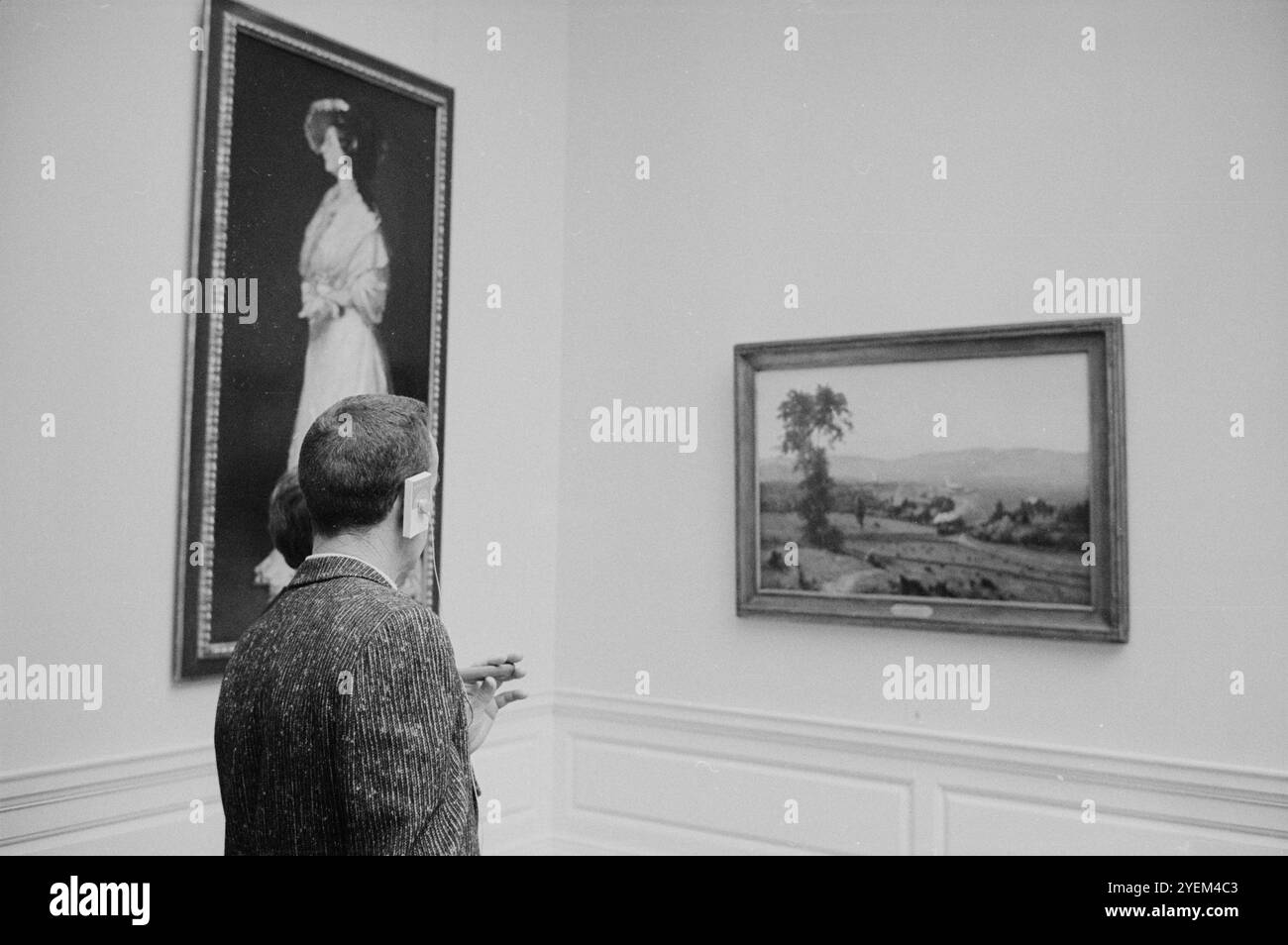 Patron with a listening device looking at paintings at the National ...