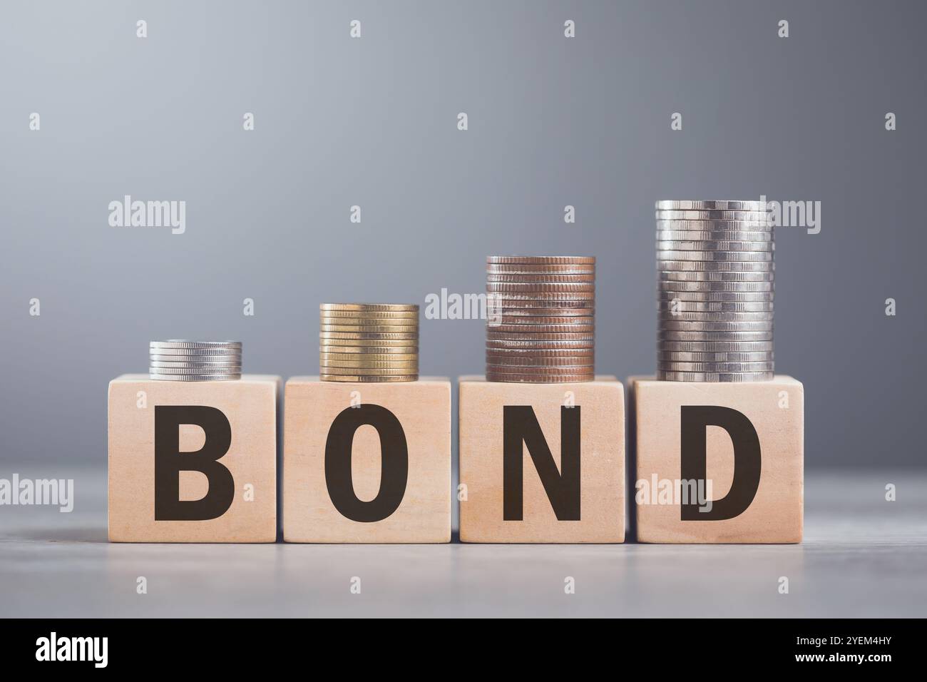 Hand stacking coins on a wooden block labeled 'BOND,' The image ...