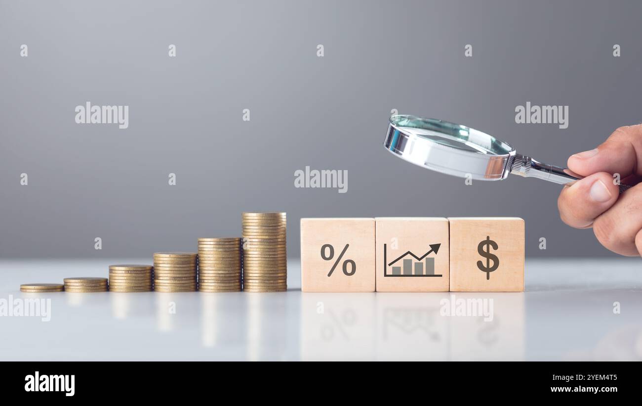A Wooden block labeled interest icons sits beside a stack of coins ...