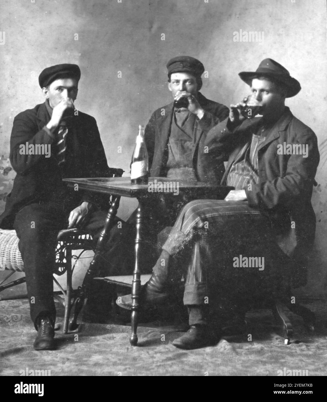 Three men sit for some serious drinking around a table, ca. 1890 Stock ...