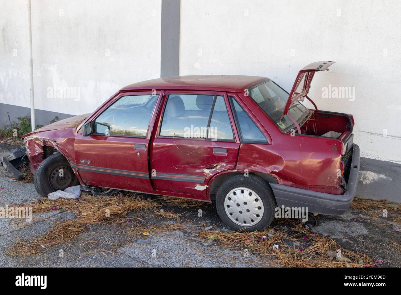 Red damaged car parked near a wall with its trunk open, showing signs ...
