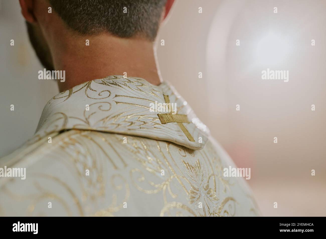 Medium close up of unrecognizable priest wearing white robe with golden ...