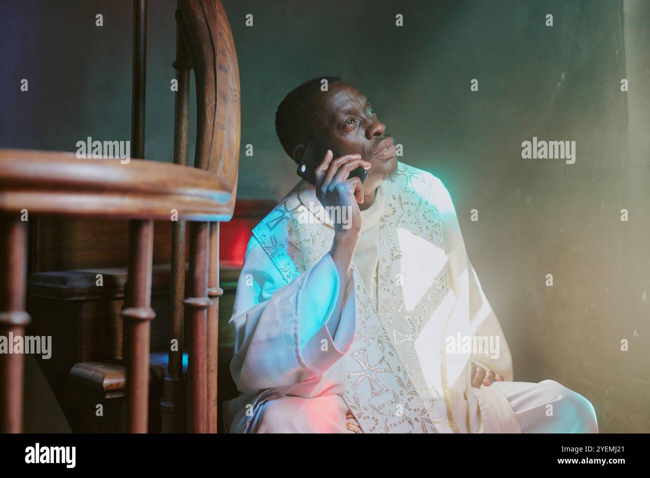 Medium close up of priest white robe with golden patterns sitting on ...