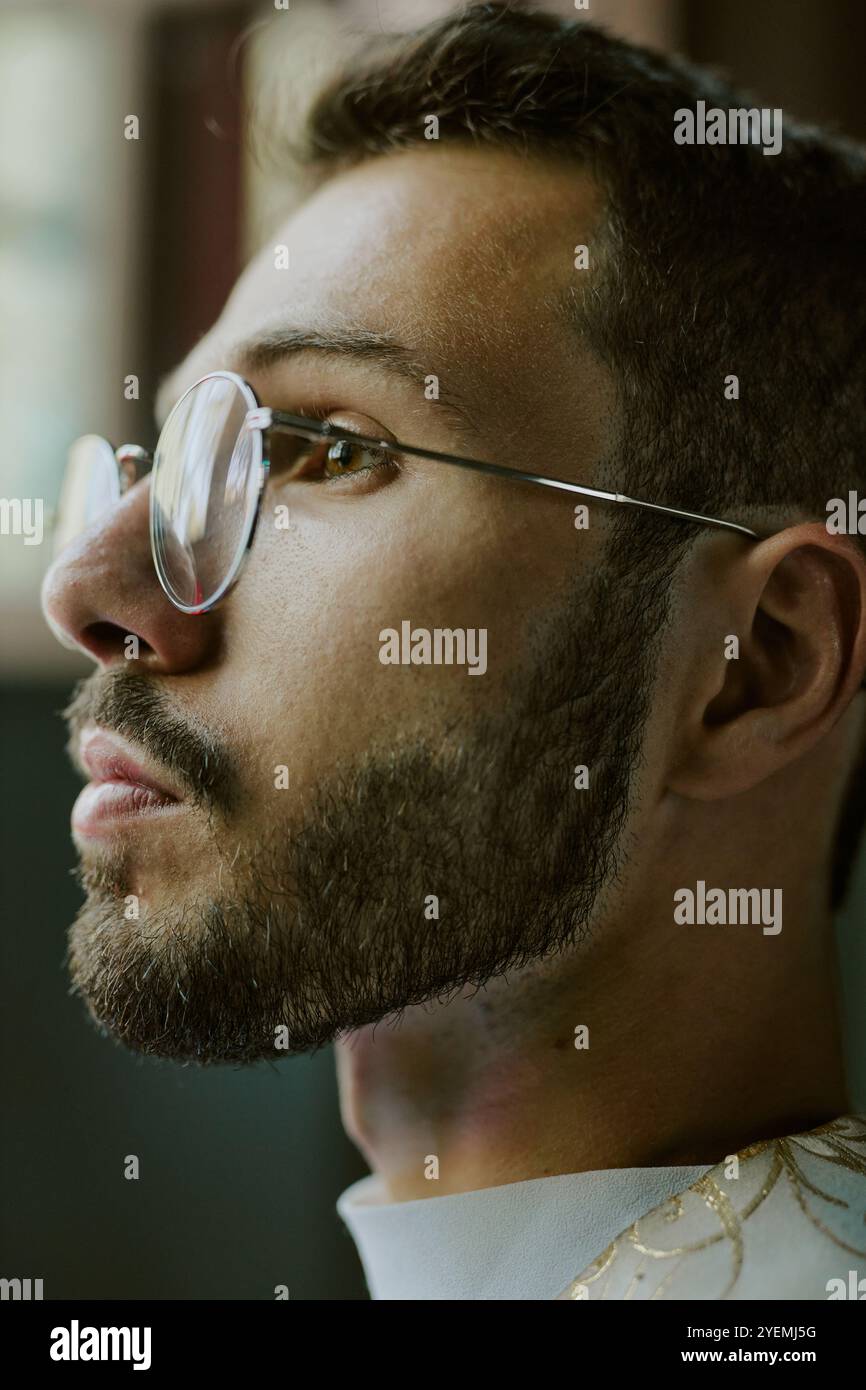 Vertical medium close up profile of young Caucasian priest with round ...