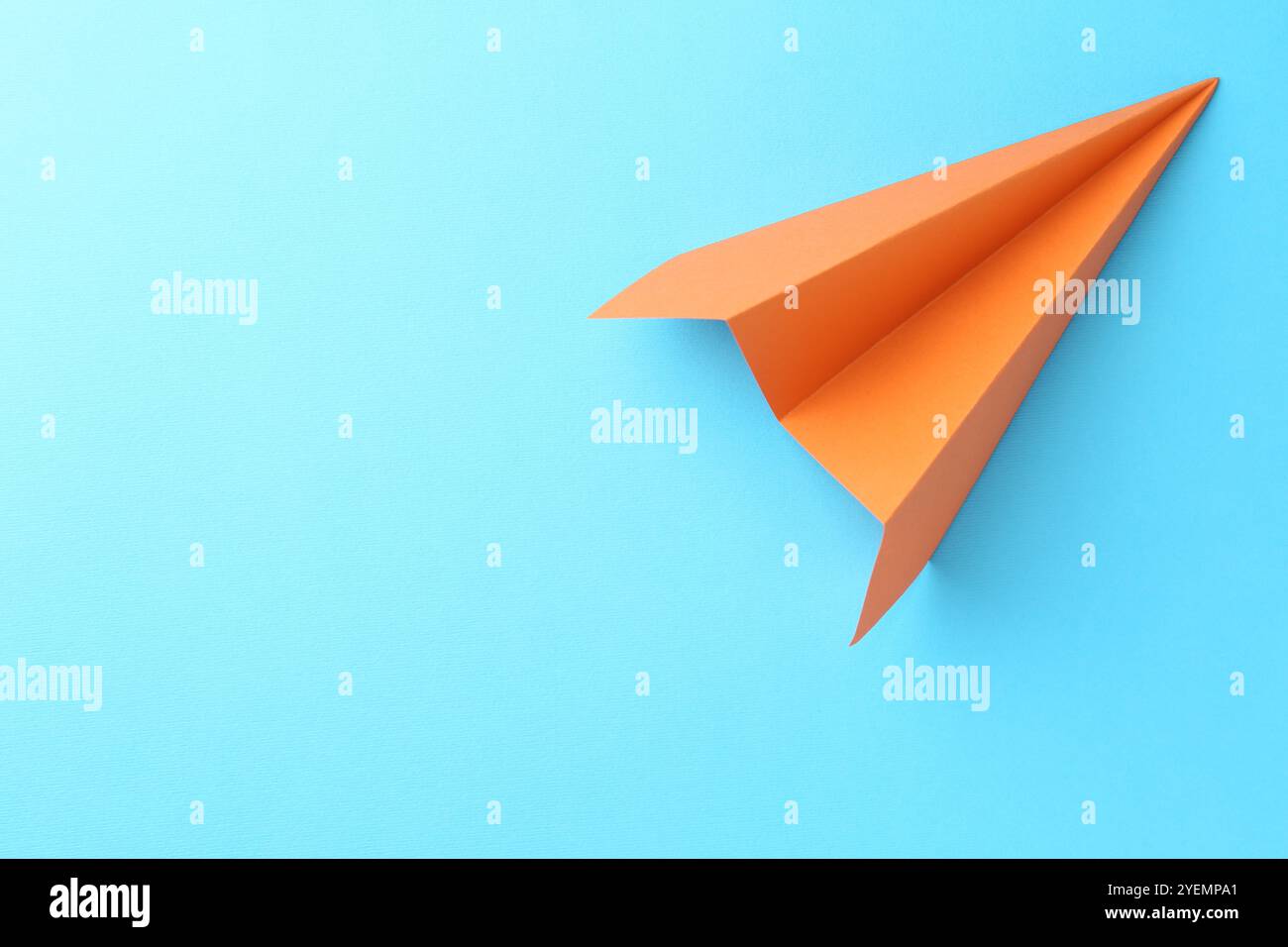 One handmade orange paper plane on light blue background, top view ...