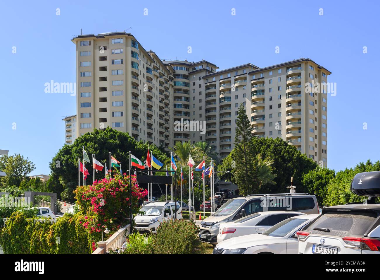 A vibrant cityscape features residential towers with colorful flags and ...