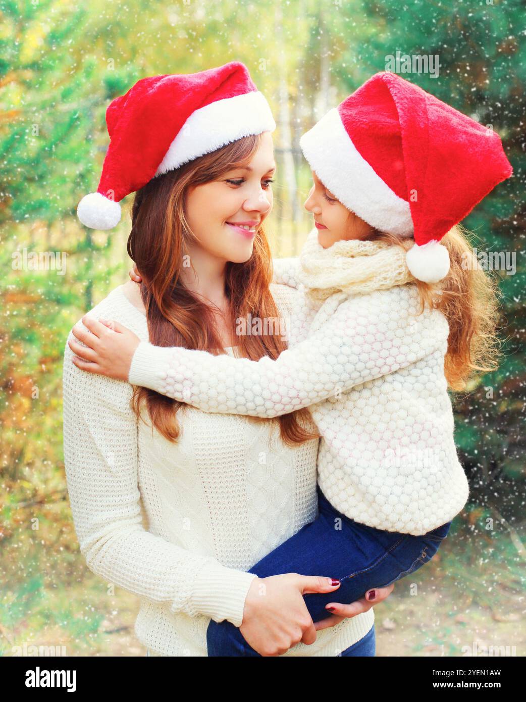 Christmas family, child hugging mother in santa red hats together over a tree having fun Stock ...