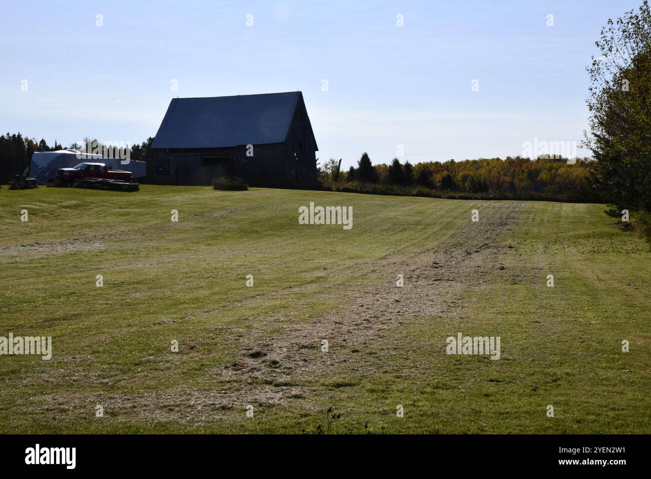 A barn in shadow with a cow pasture in the foreground Stock Photo - Alamy
