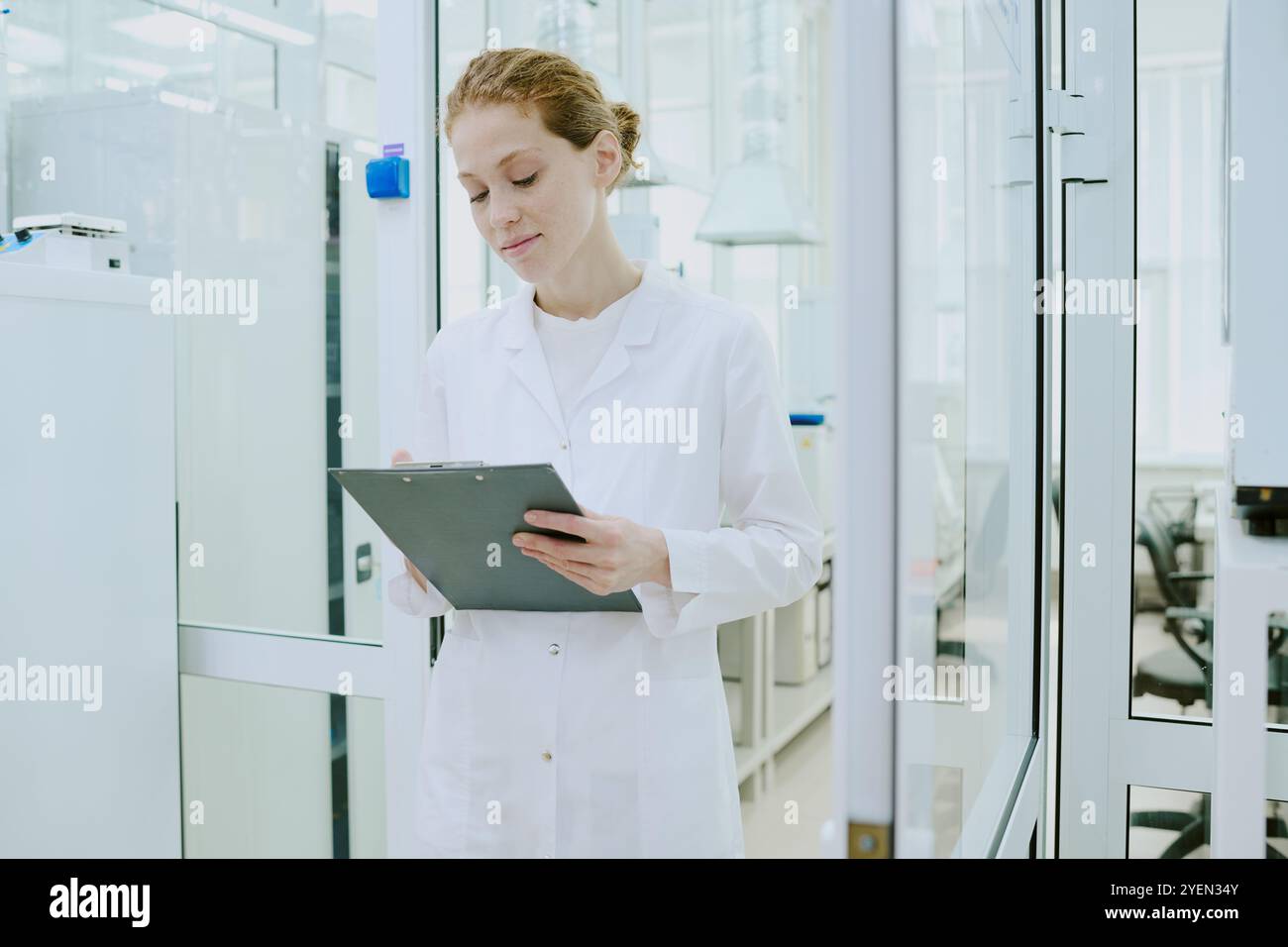 Scientist wearing a lab coat while holding a clipboard smiling ...