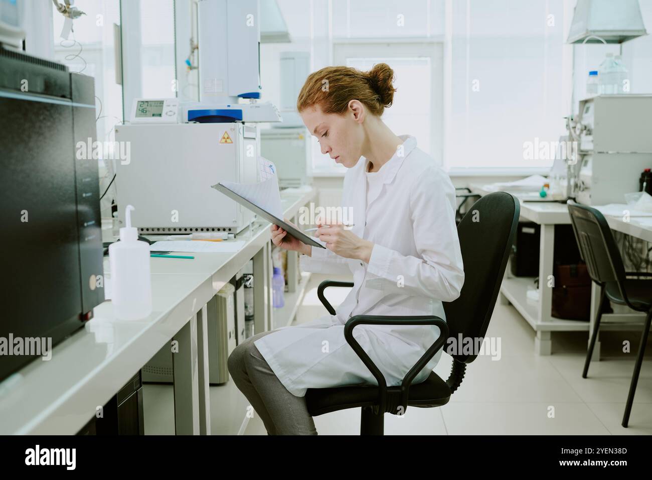 Woman scientist in white coat analyzing data in modern laboratory ...