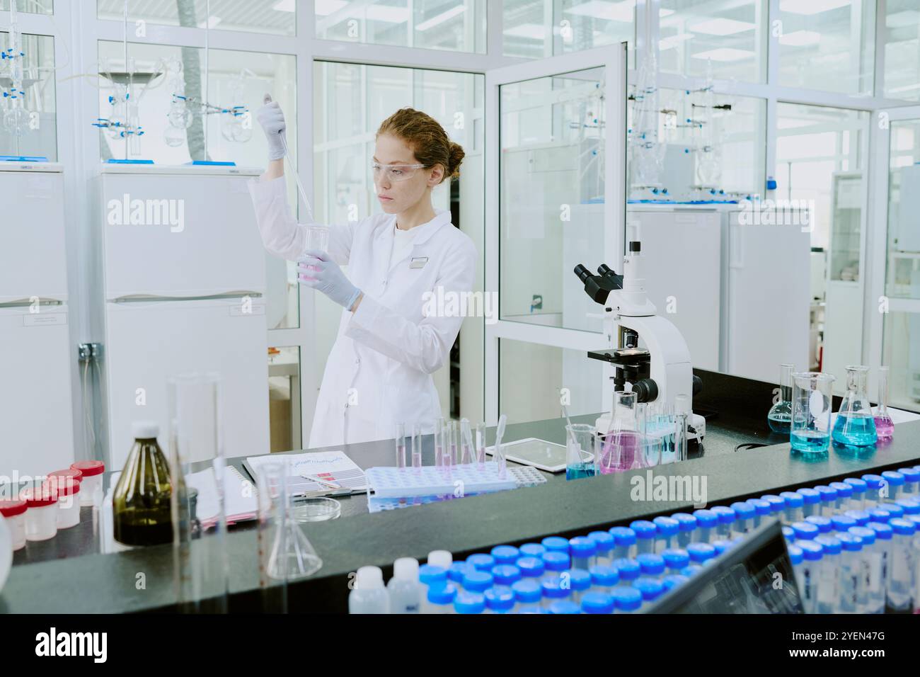 Scientist in white lab coat conducting experiments in advanced laboratory setup with various ...