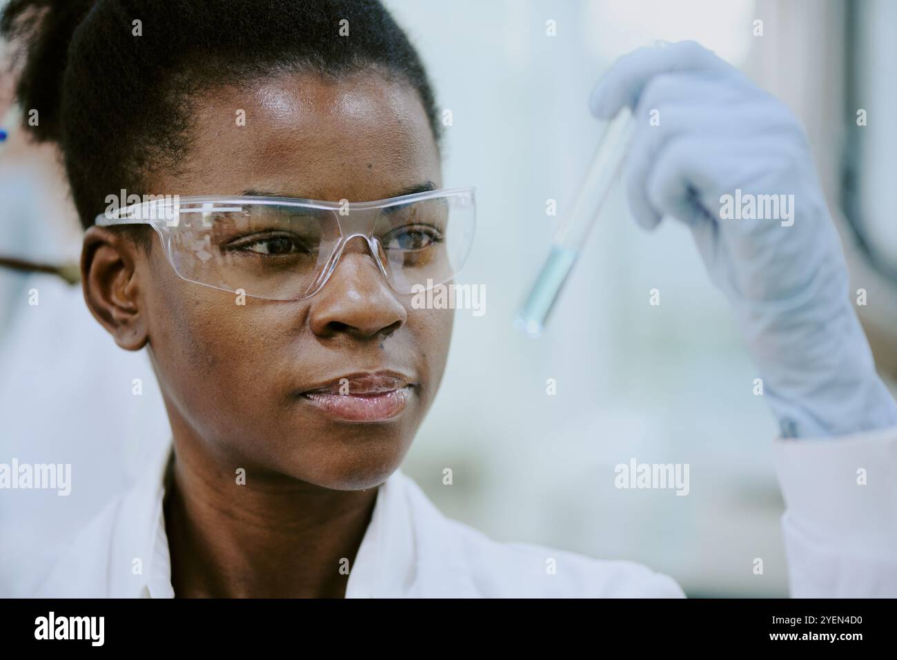 Lab technician examining test tube with protective glasses during ...