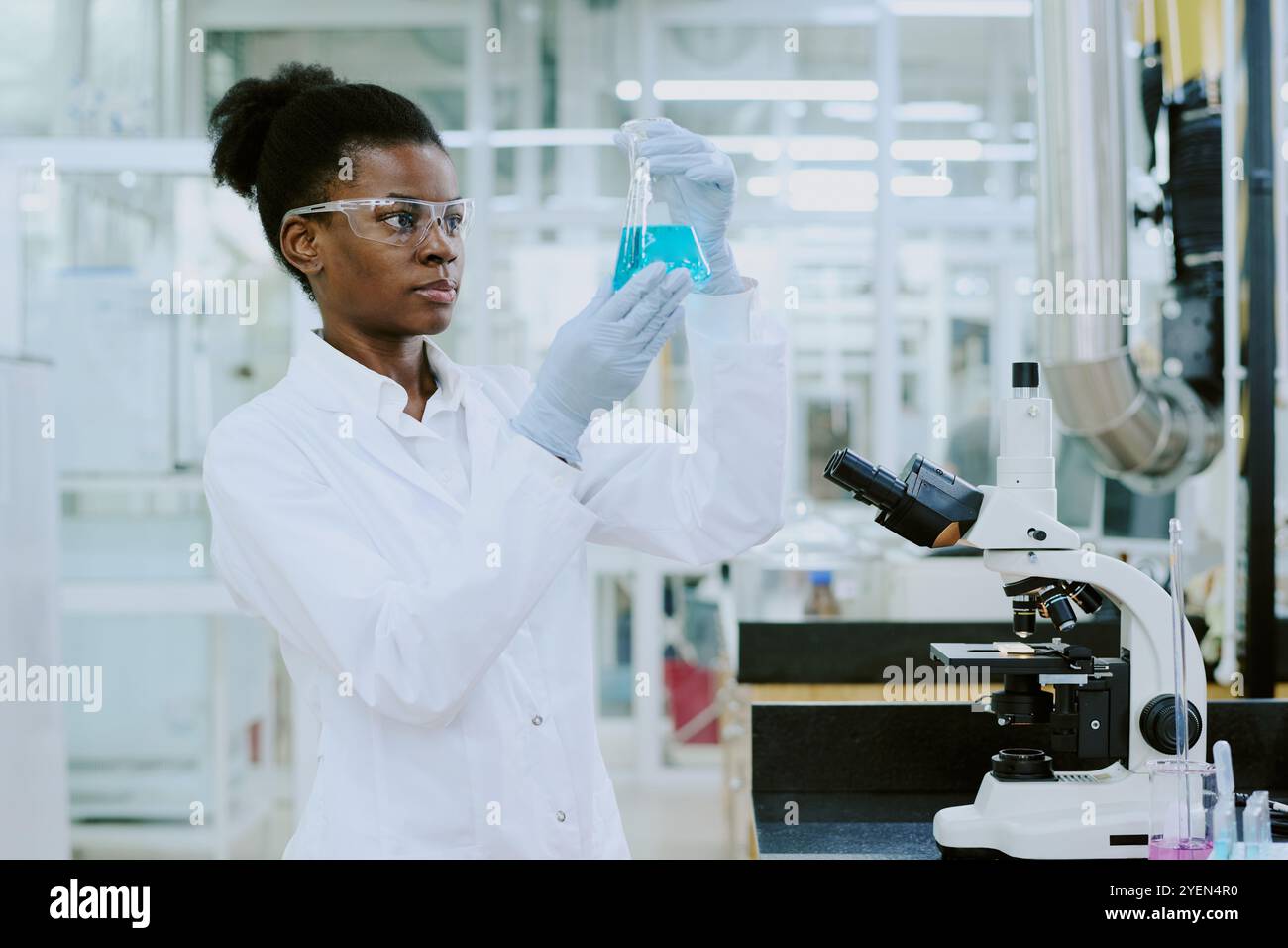 Black scientist analyzing a blue liquid sample in modern laboratory ...