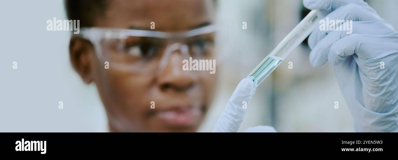 Close-up of scientist conducting scientific experiment with pipette, wearing safety goggles ...