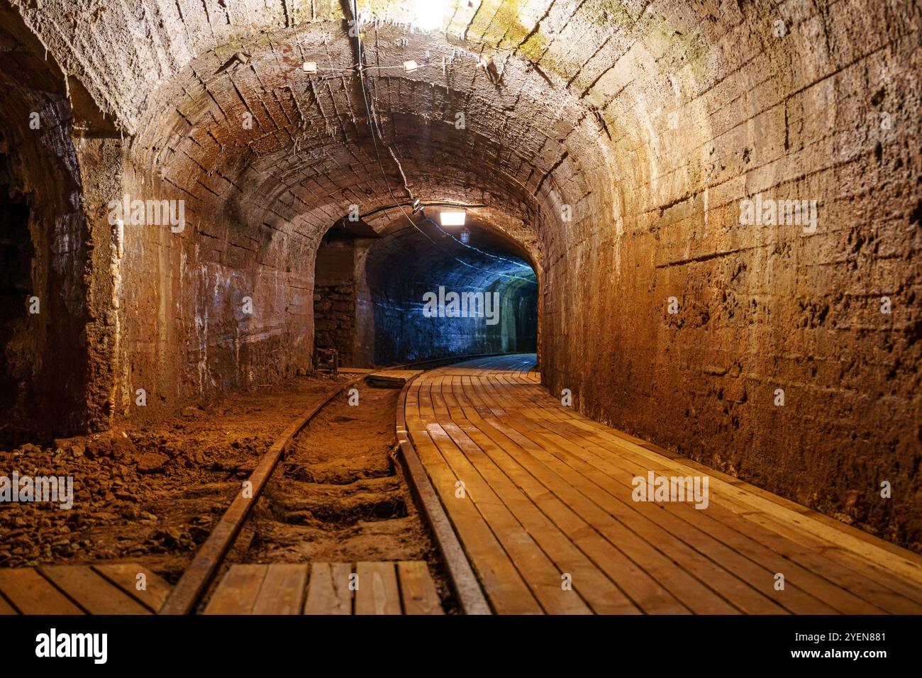 Old mine tunnel with wooden walkway and tracks through the center of ...