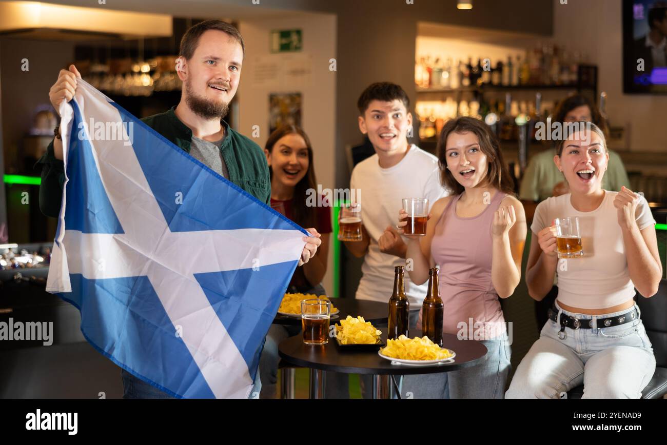 Football fans waving the flag of Scotland while drinking beer and ...