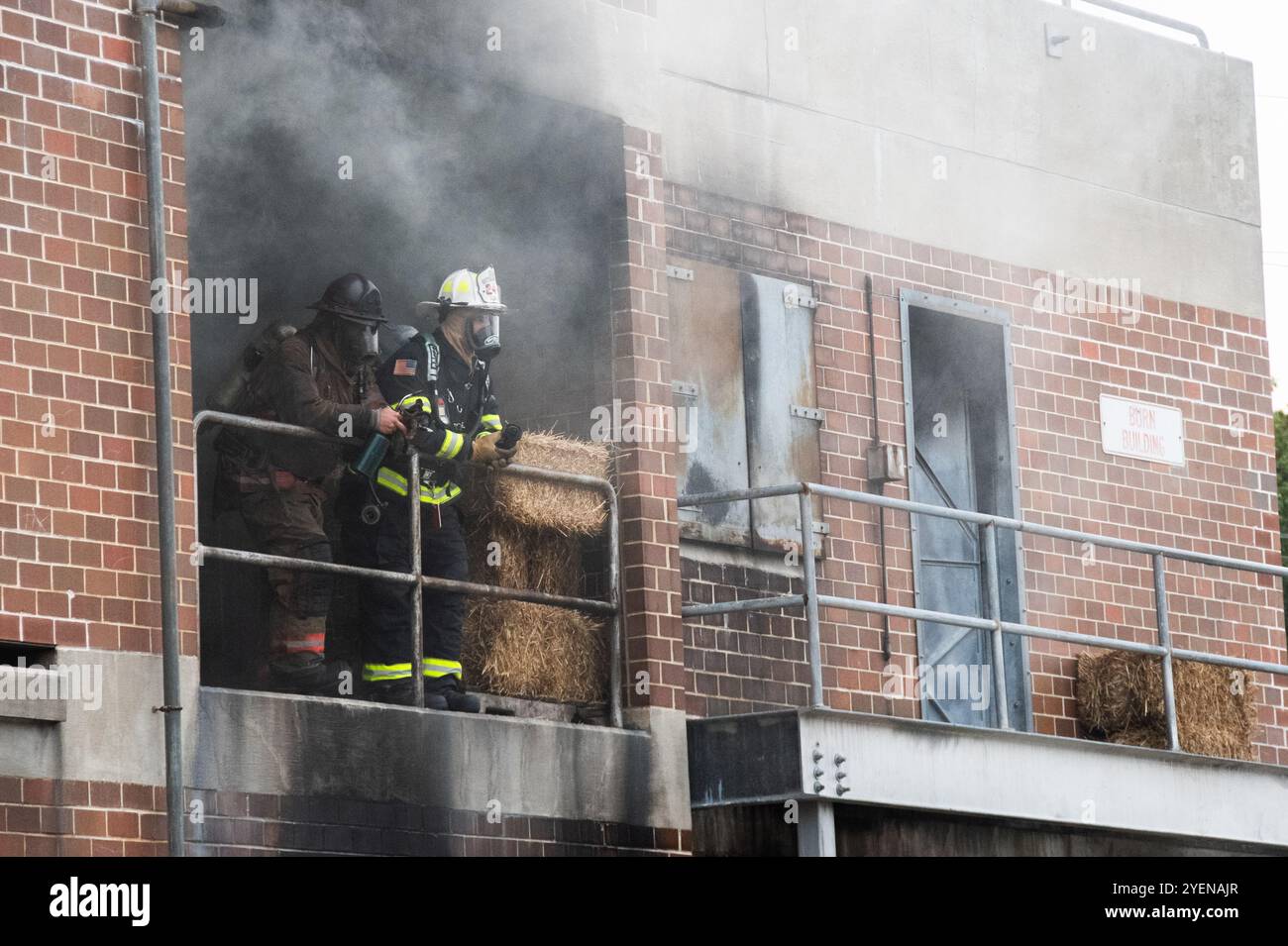 Two fire instructors stand on the balcony of a controlled burn ...