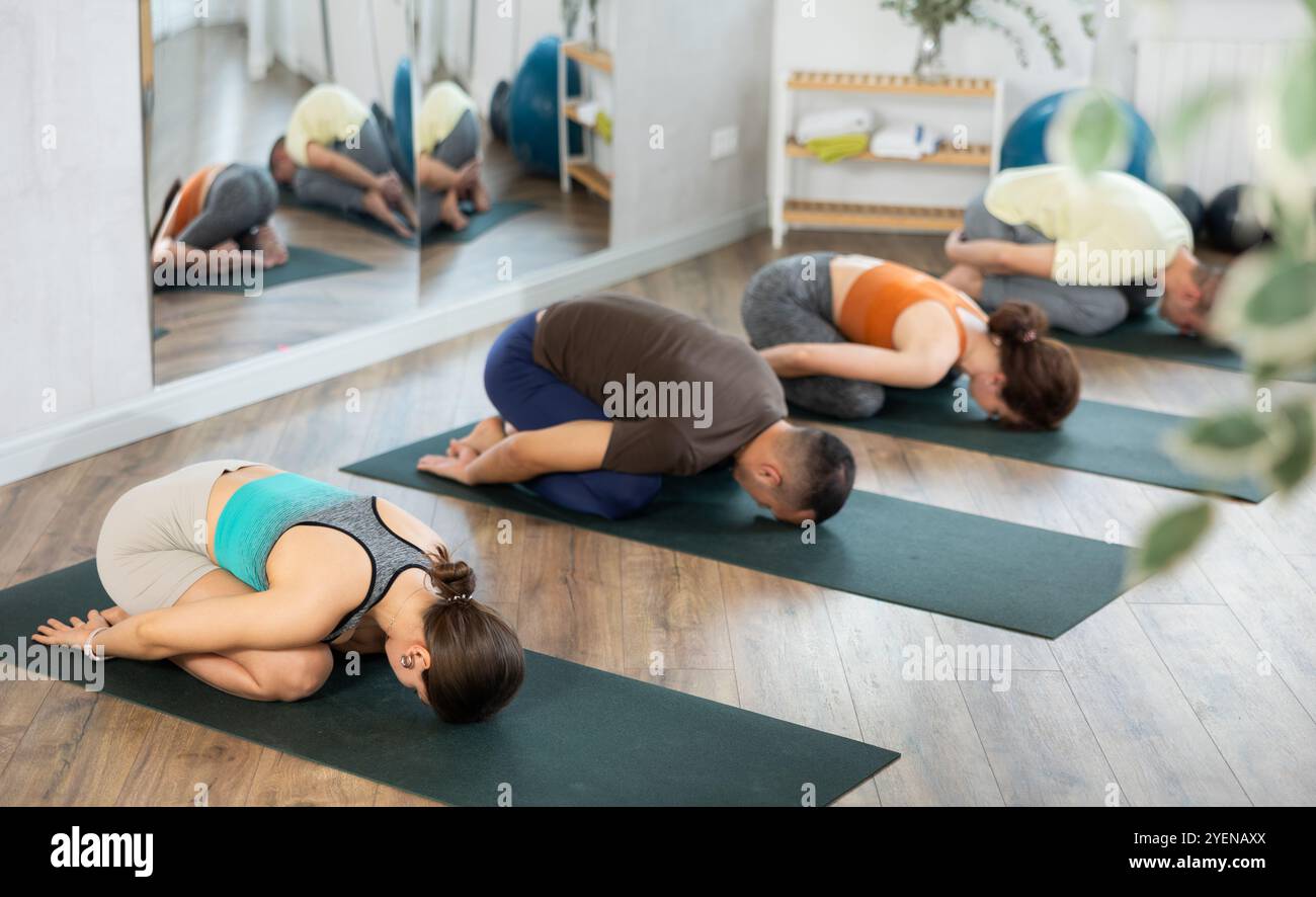 Women and men relaxing and stretching in sleeping pigeon pose Eka Pada Rajakapotasana during ...