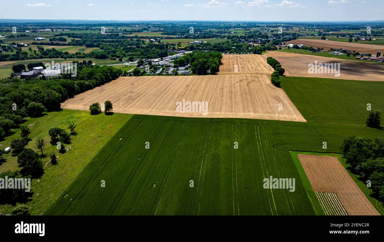 A sweeping aerial view shows varied farmland with lush green fields ...