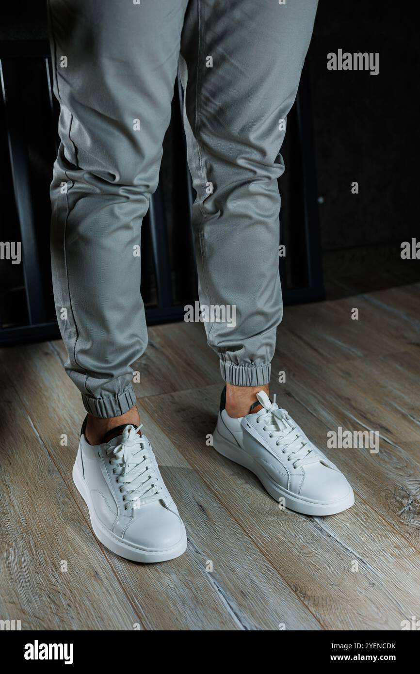 Men's summer shoes. Close-up of male legs in white leather sneakers ...