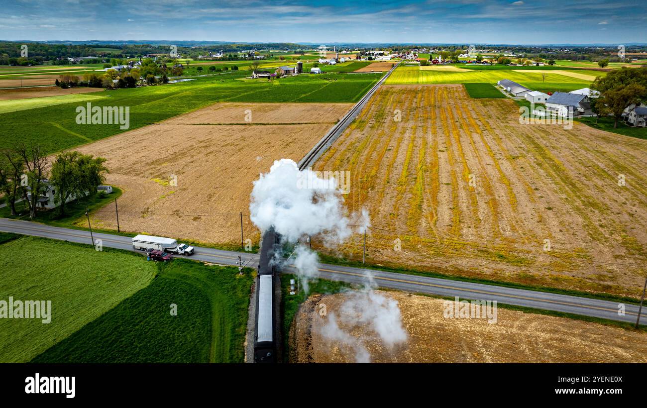 A vintage steam train steams along tracks nestled between expansive ...