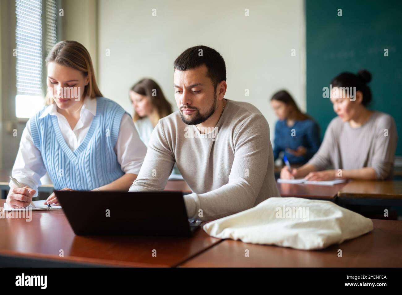 Group of adult students sitting at tables in classroom Stock Photo - Alamy