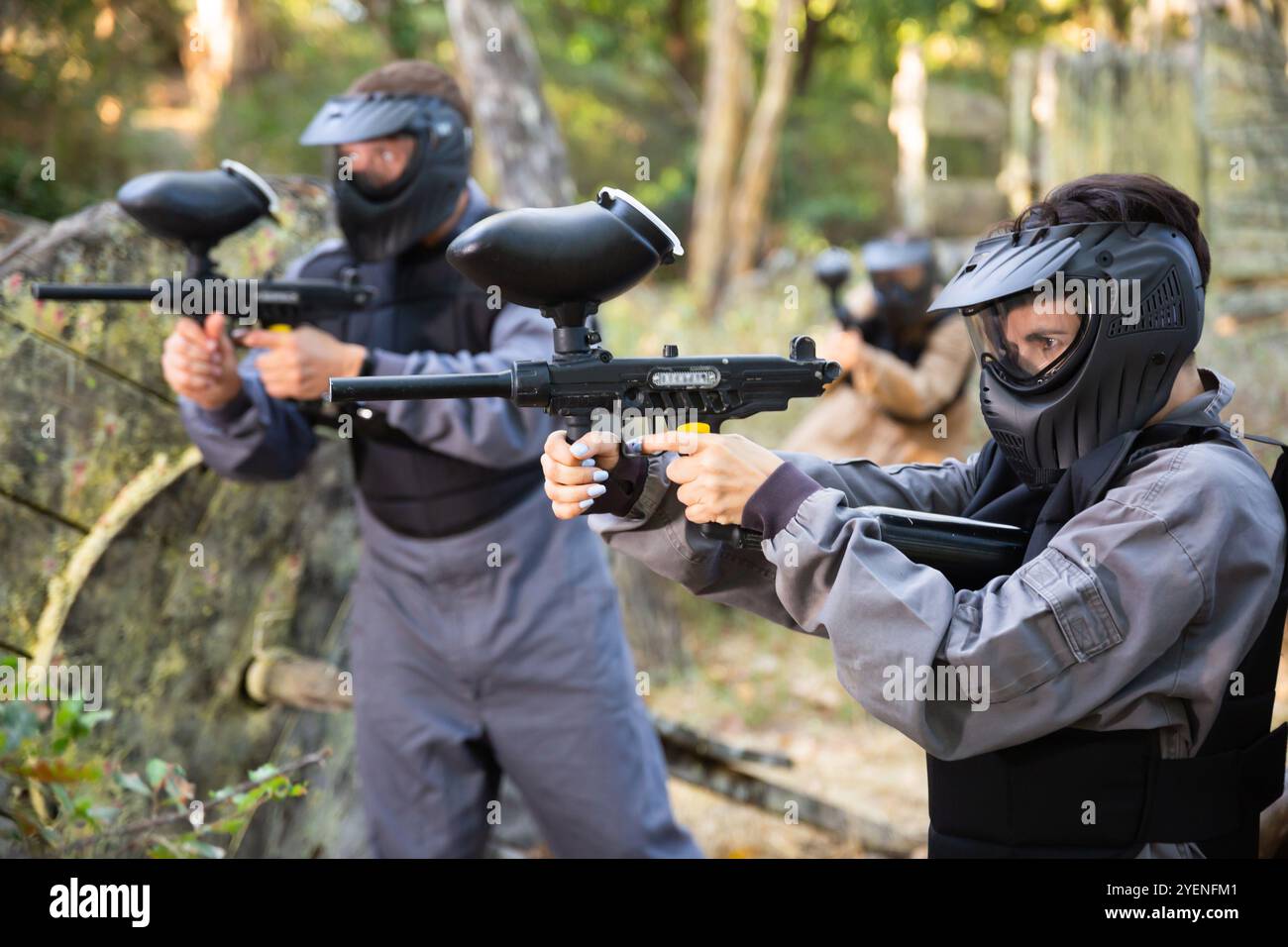 Paintball players aiming and shooting with guns at opposing team Stock ...