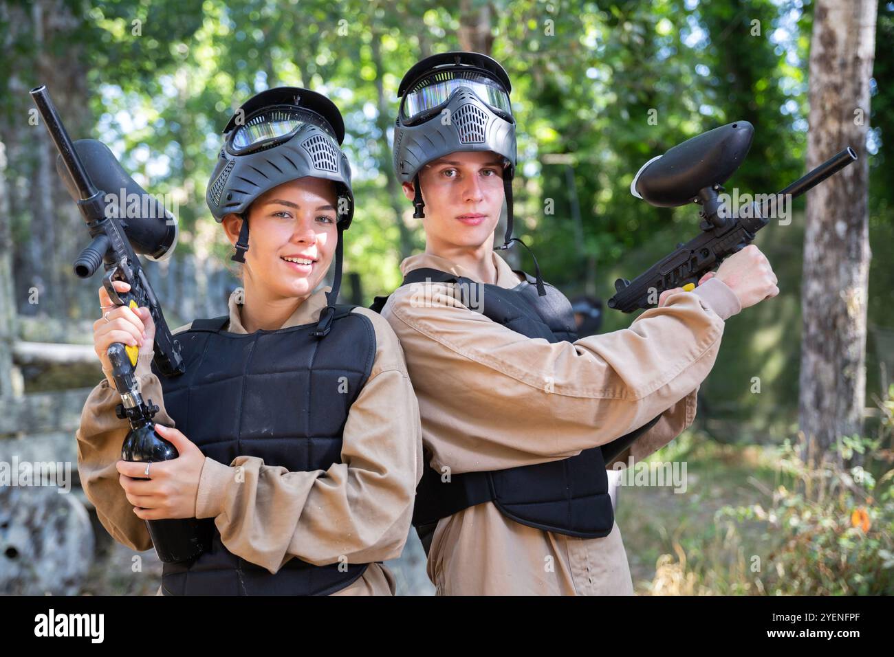 Man and woman in camouflage and masks with guns pose back to back while ...
