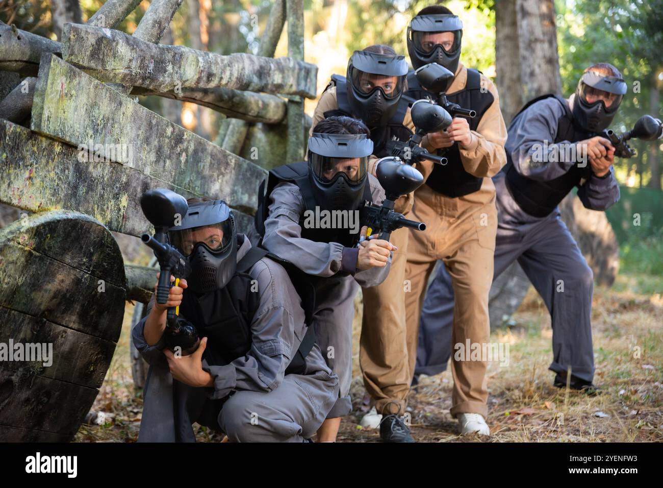 Group of paintball players aiming and shooting with guns outdoors Stock ...