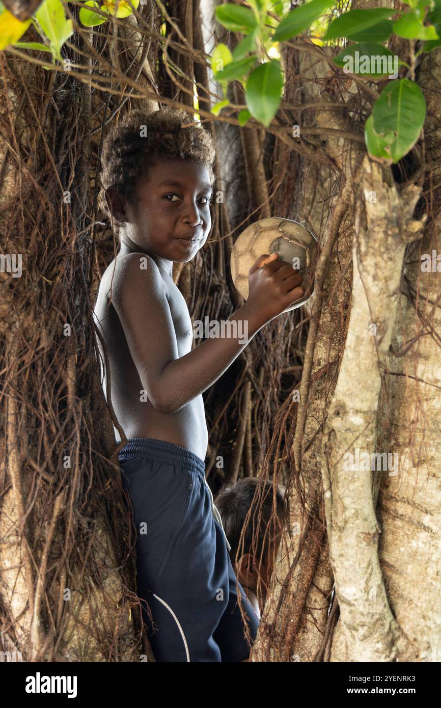 Young boy hiding in a tree with soccer ball smiling Stock Photo - Alamy