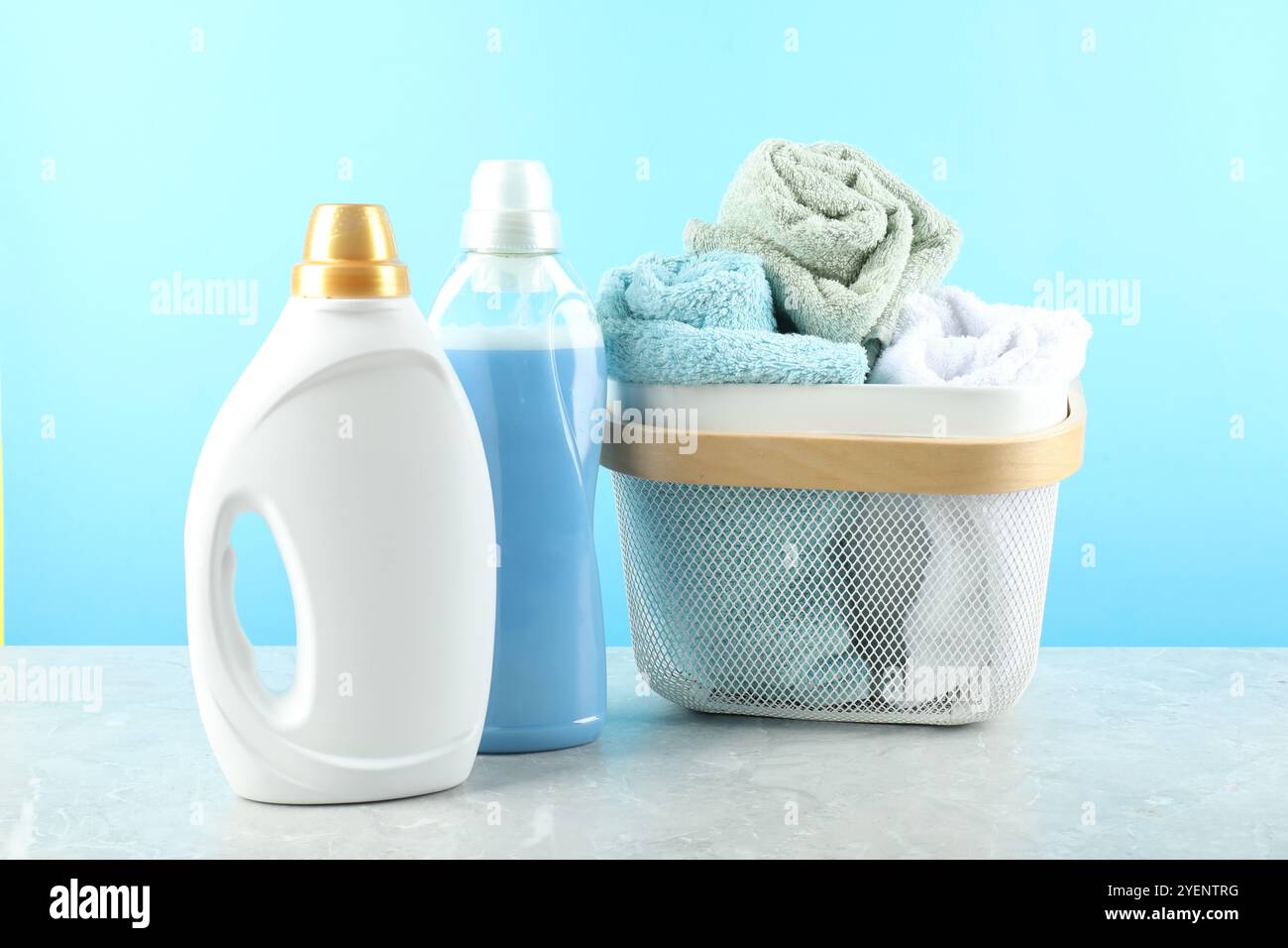 Laundry detergent in bottles and towels on grey marble table against ...