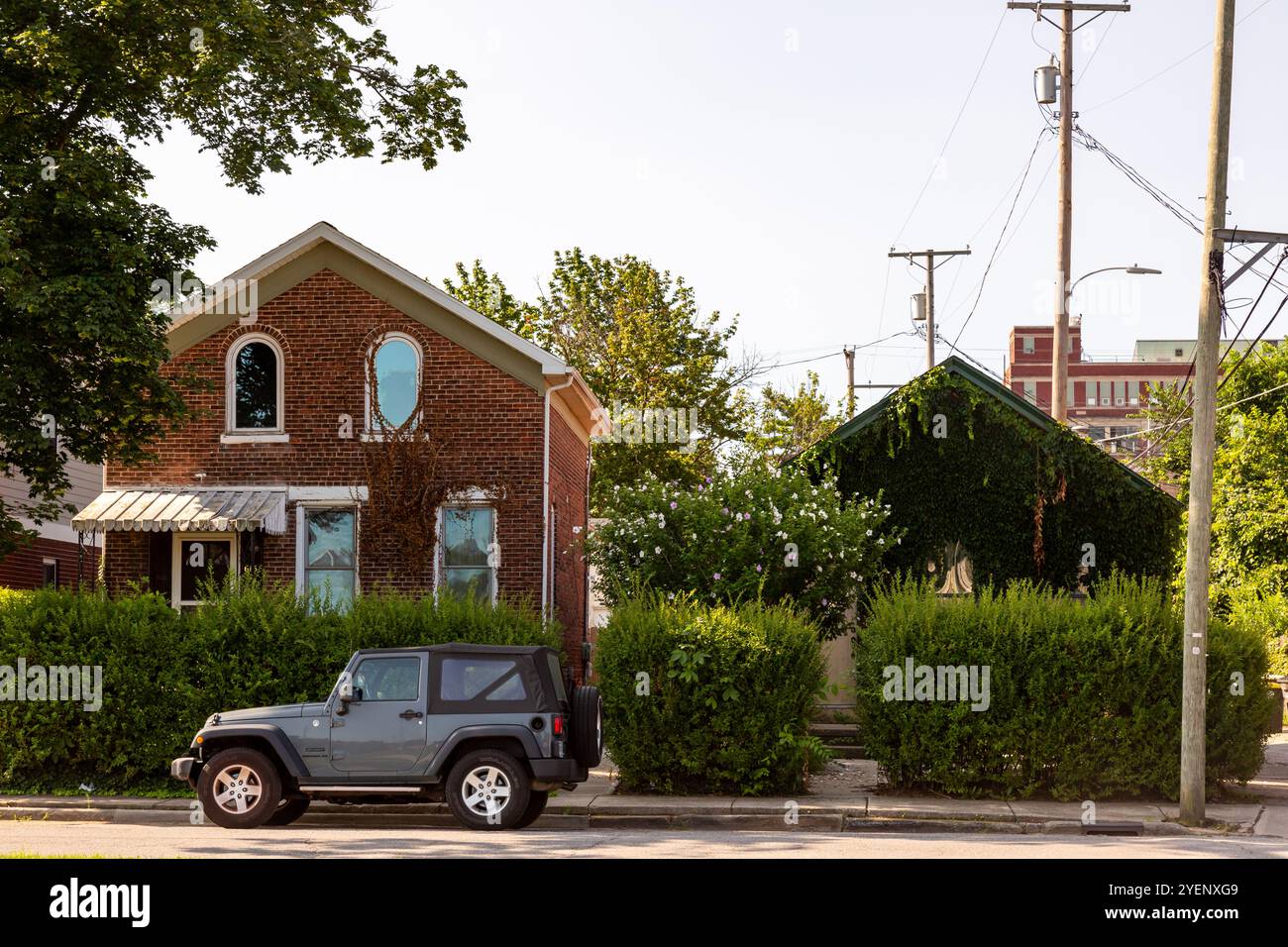 A gray Jeep is parked in front of an old brick house with an ivy ...