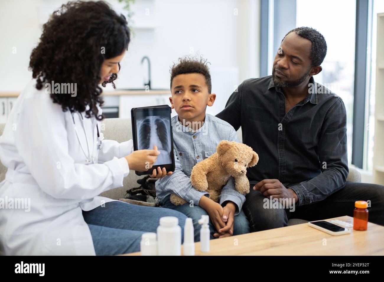 Female doctor shows lung x-ray to sick boy with father at home Stock ...