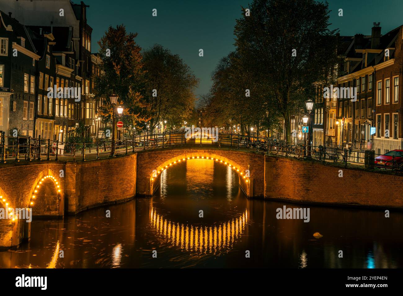 Amsterdam’s historic canal bridges illuminated at night. The ...