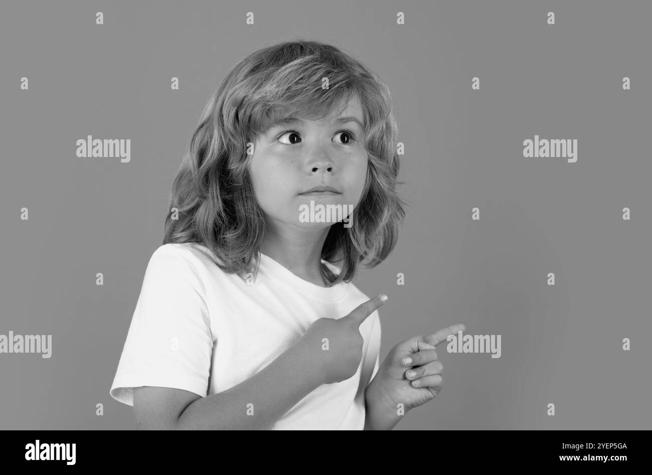 Child boy looking away, pointing finger on isolated studio background ...