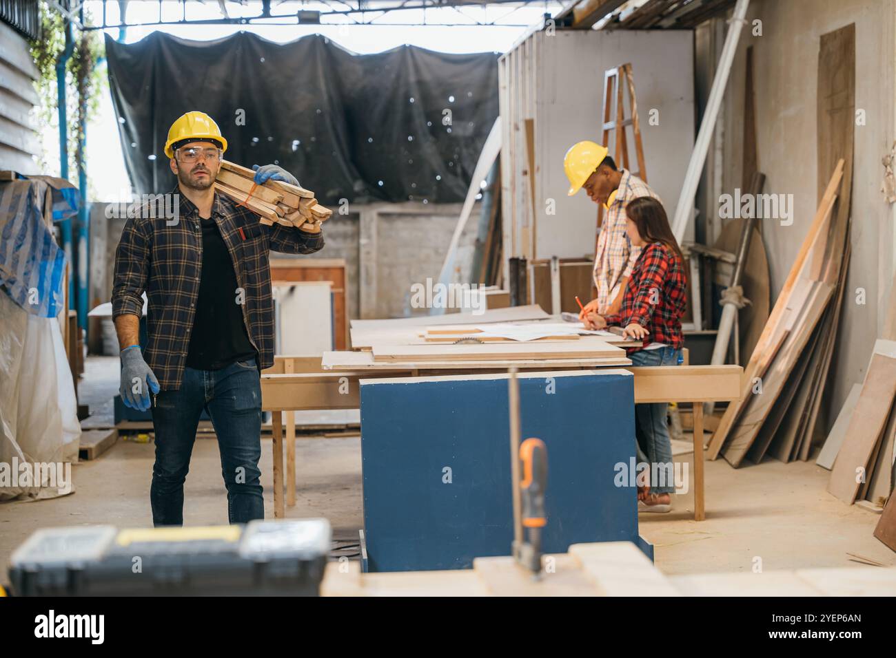 Construction carpenter carrying wood planks on his shoulder, wearing a ...