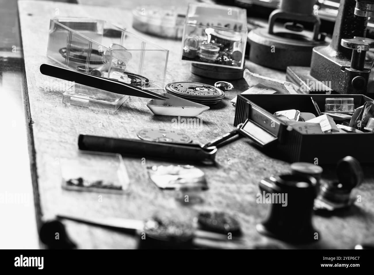 Watchmaker's bench with scattered tools and components, including ...
